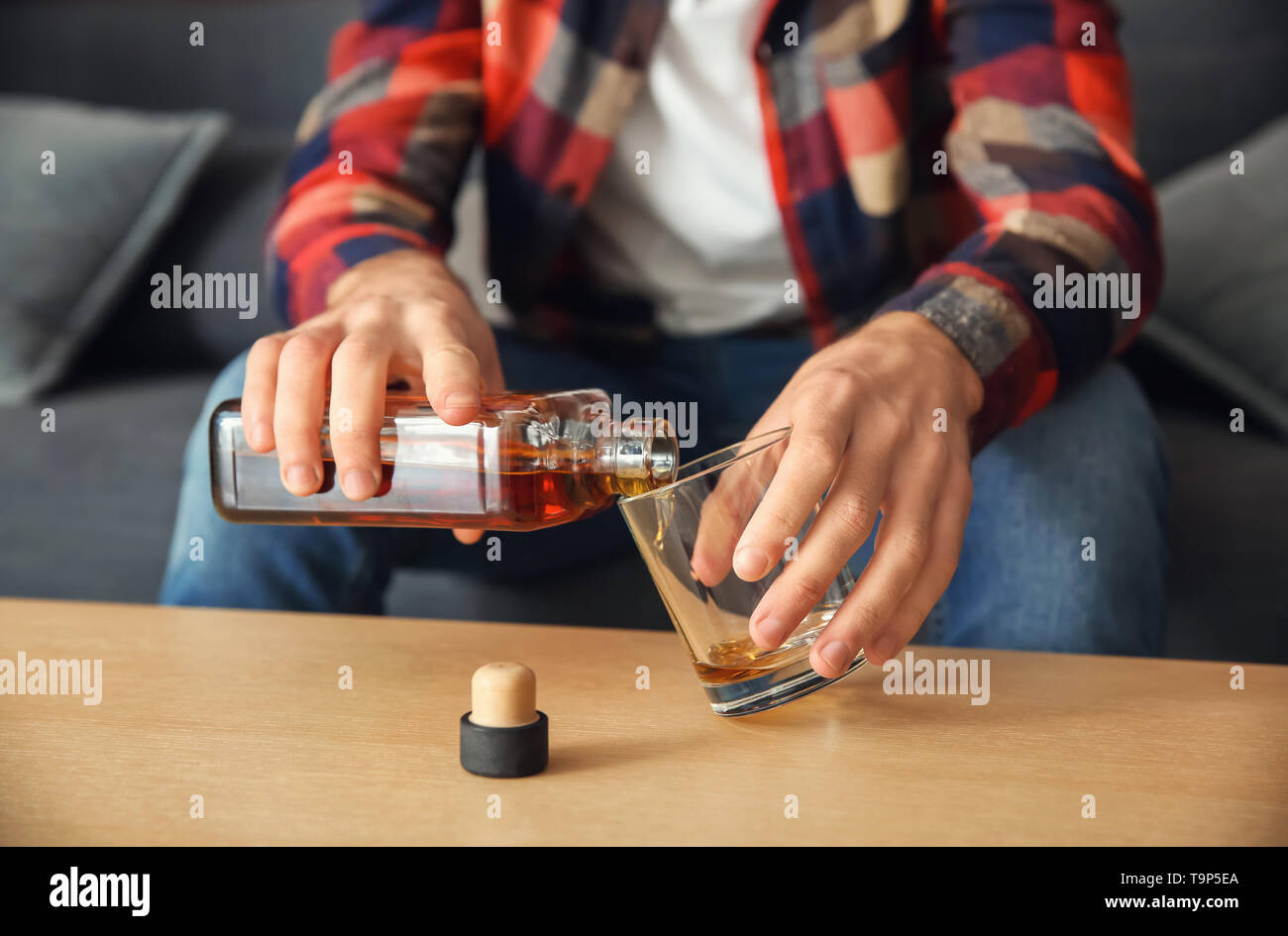 Man pouring alcohol from bottle into glass at table, closeup ...