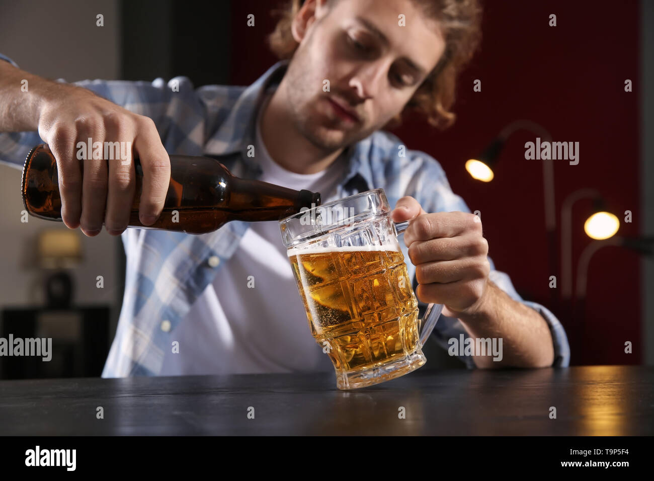 Depressed young man drinking beer at table. Alcoholism concept Stock ...
