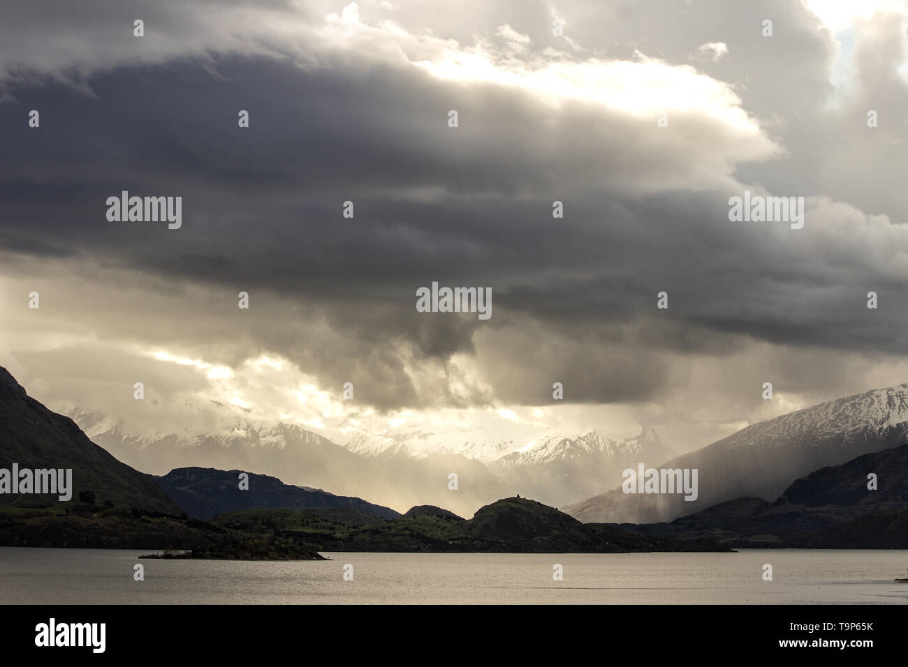 Mountain lake landscape with light sun rays and dark storm clouds sky ...
