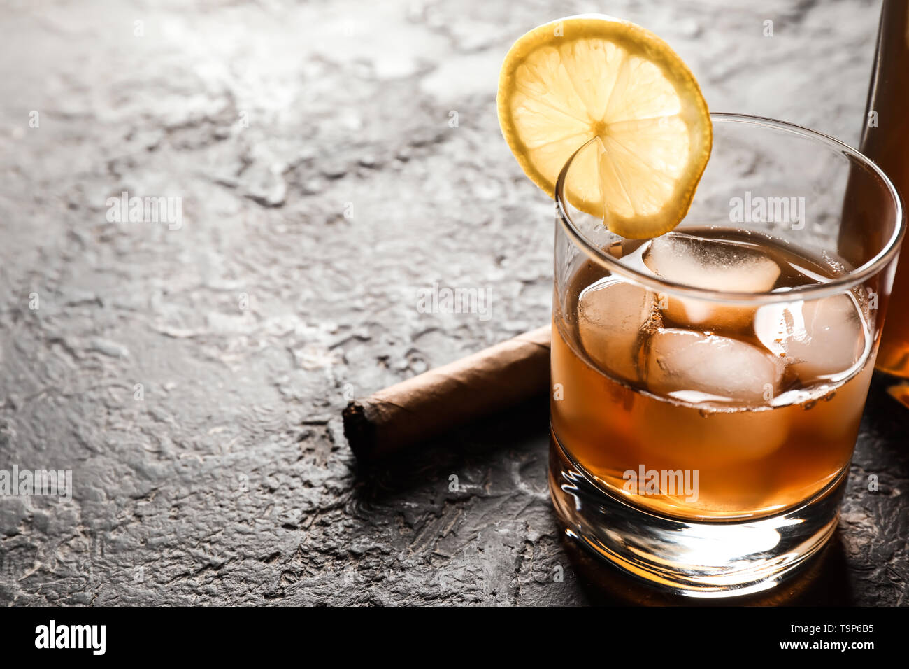 Glass of cold whiskey with cigar on grunge background Stock Photo - Alamy