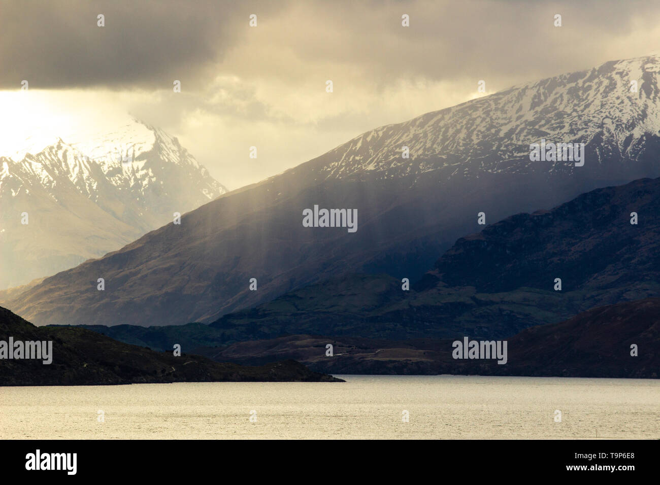 Mountain lake landscape with light sun rays and dark storm clouds sky ...