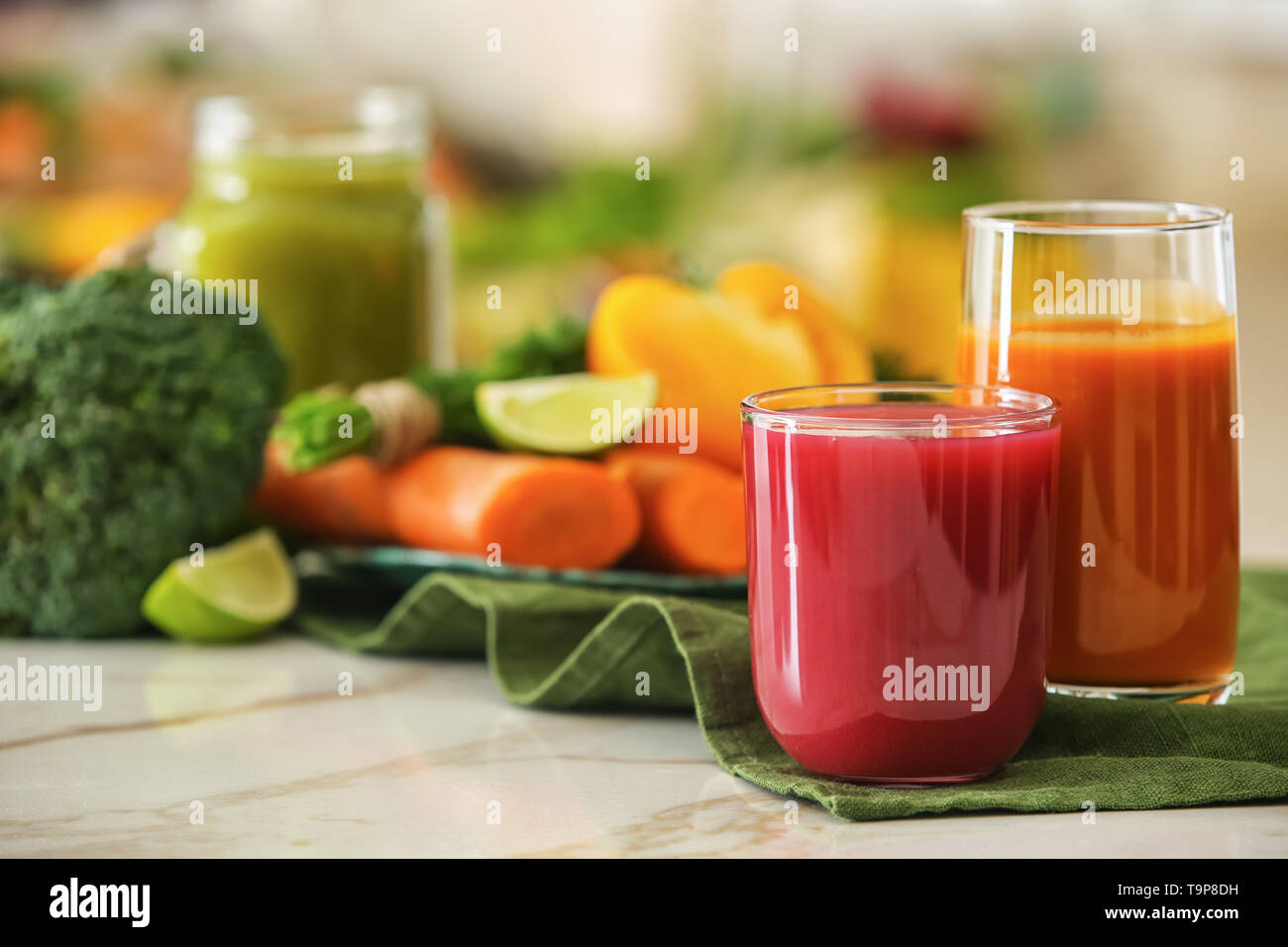 Glasses of healthy vegetable juice with ingredients on light table ...