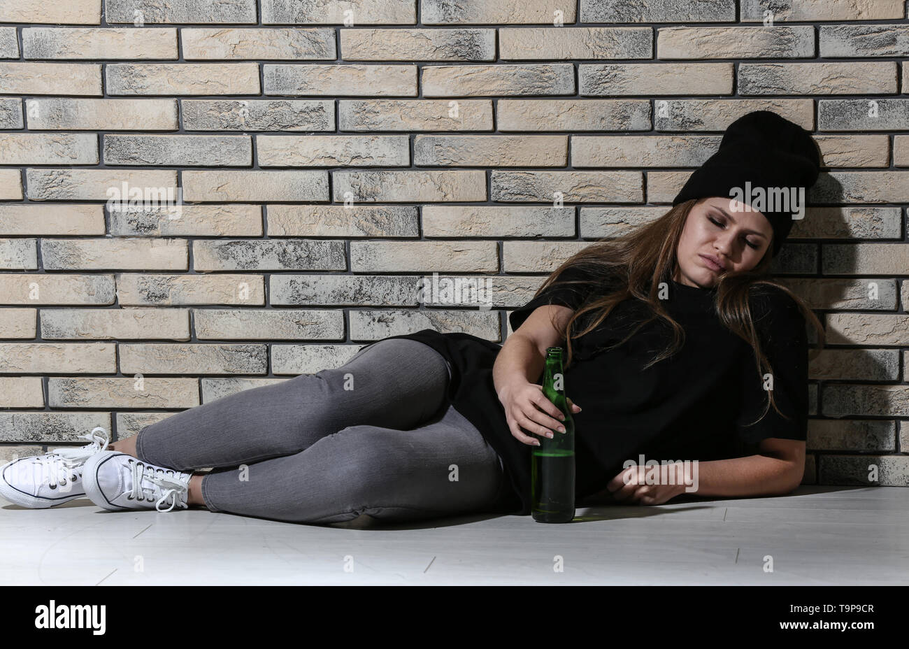 Depressed drunk woman near brick wall Stock Photo - Alamy