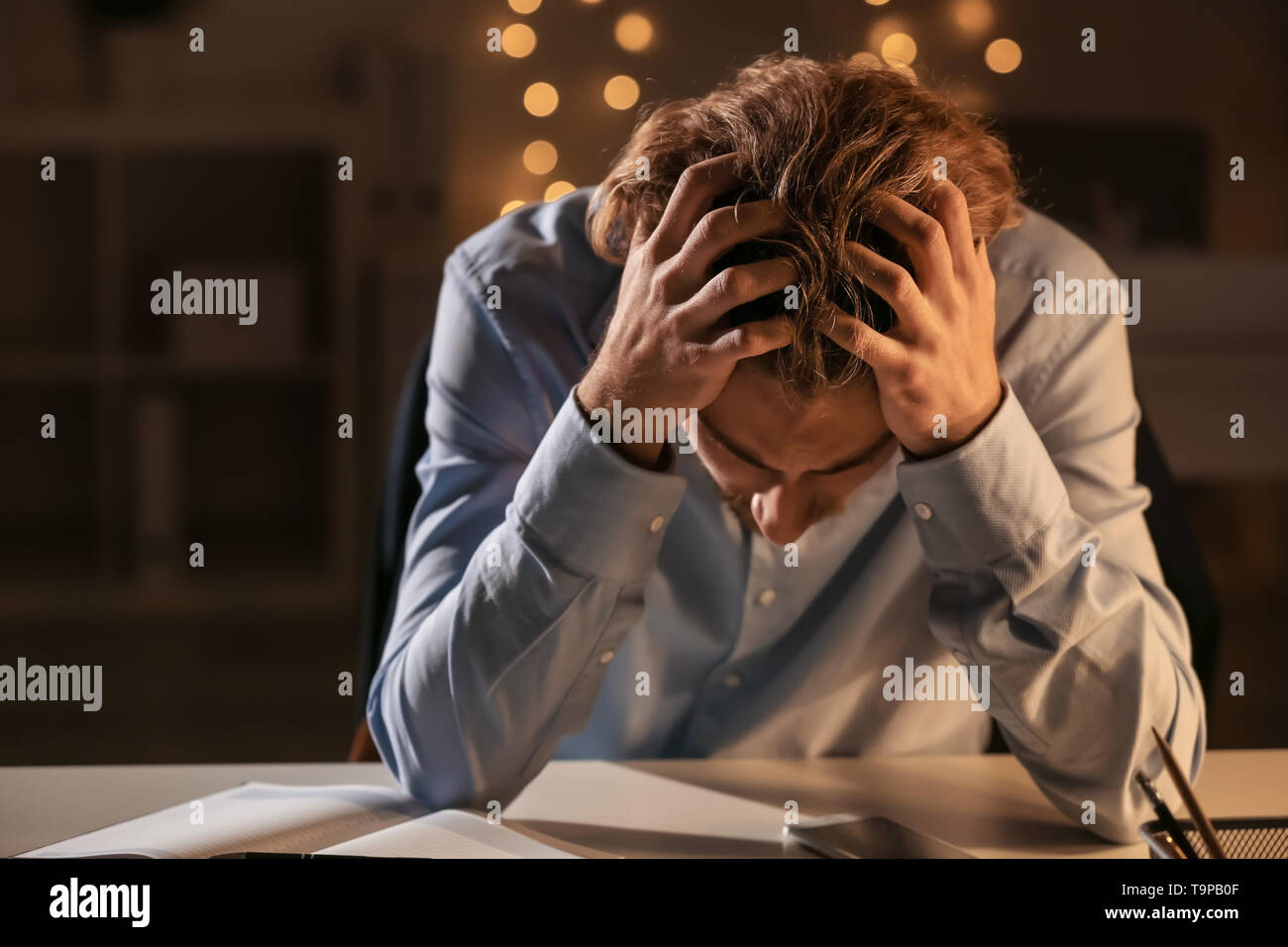 Young man suffering from headache late in evening Stock Photo - Alamy