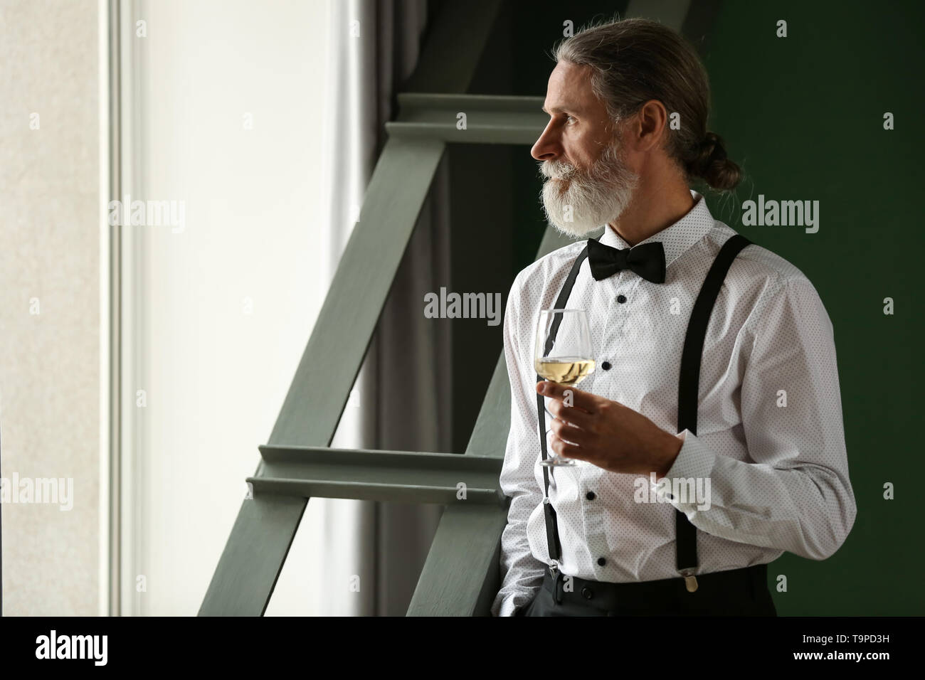 Senior gentleman drinking wine near window at home Stock Photo - Alamy