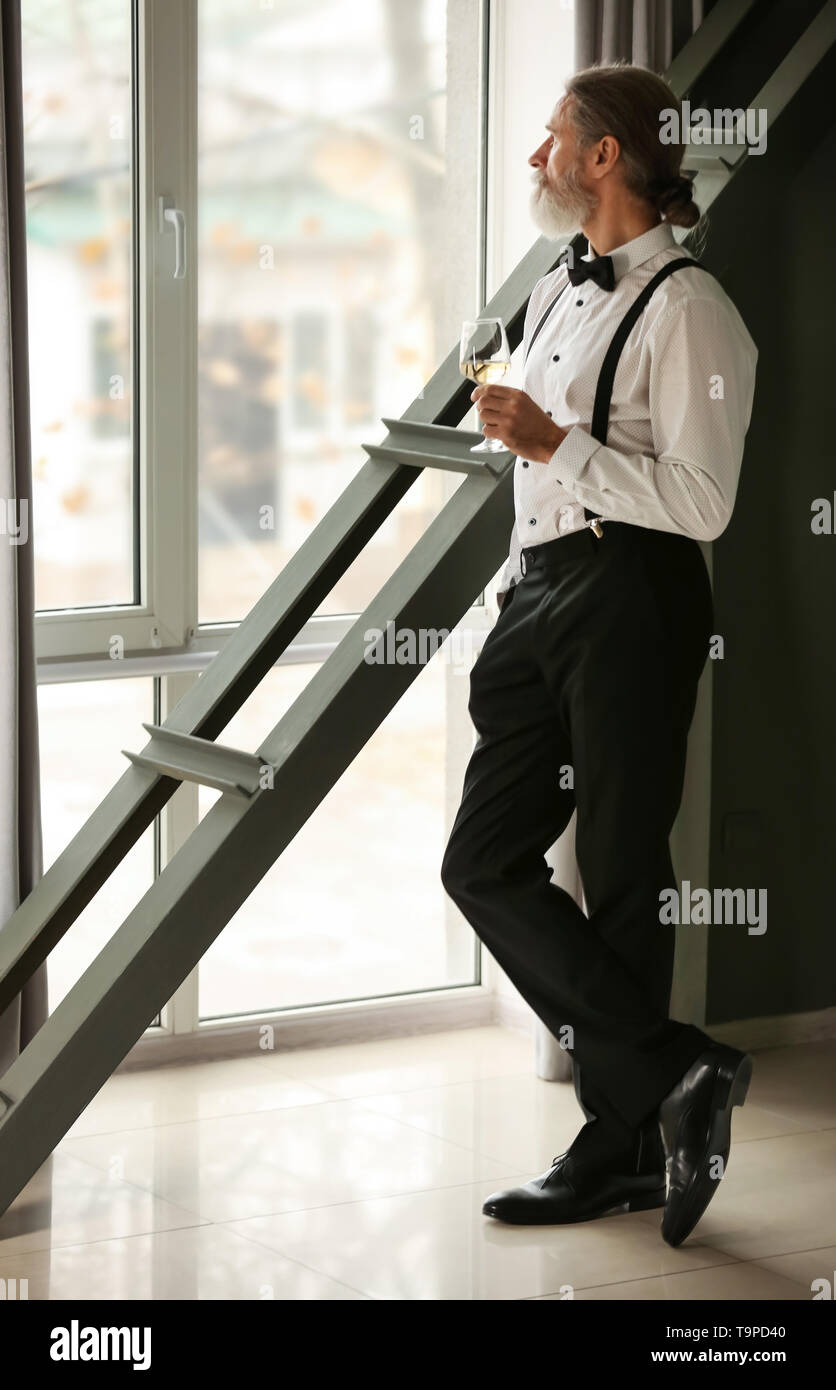 Senior gentleman drinking wine near window at home Stock Photo - Alamy