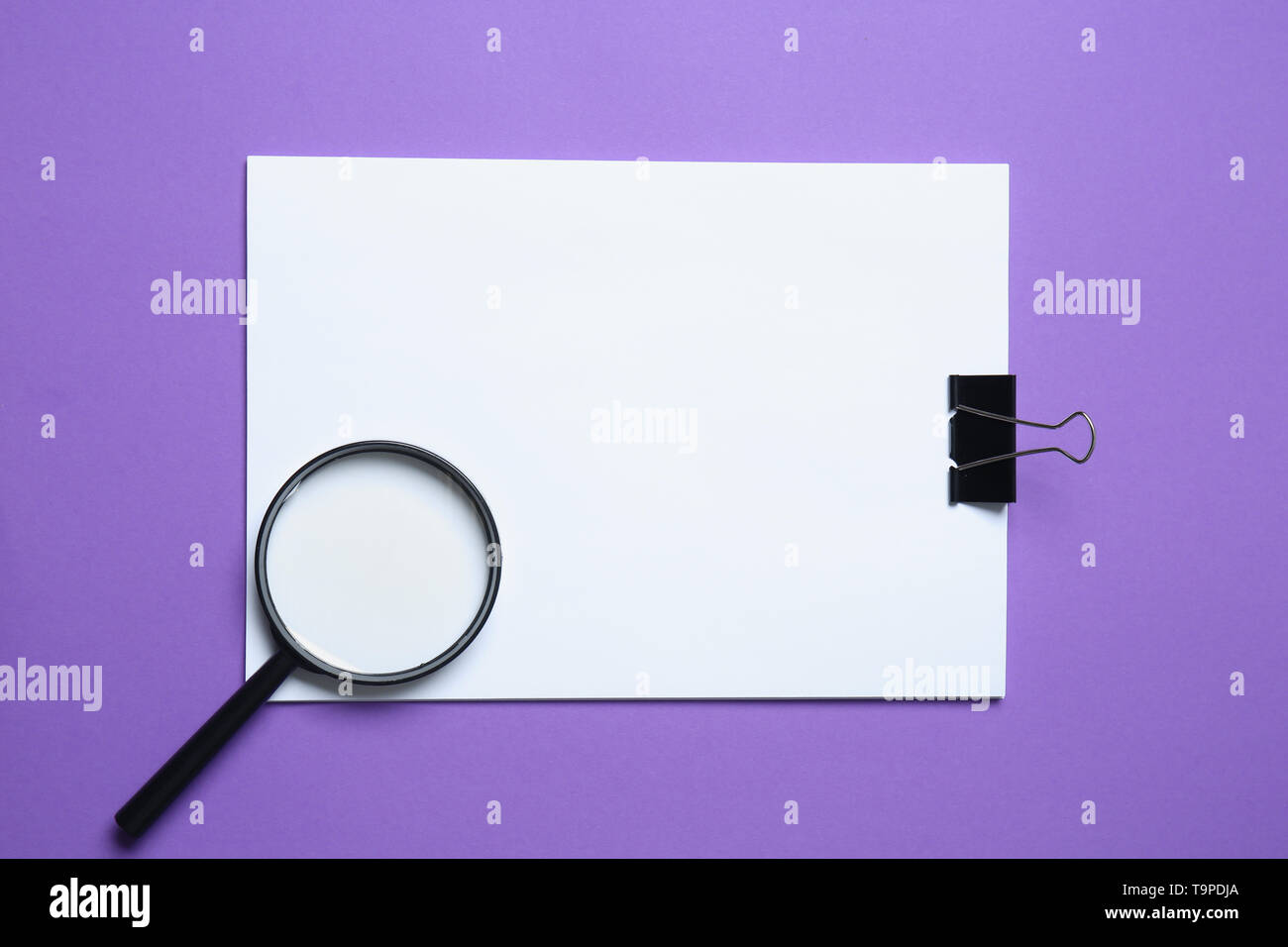 Blank sheets of paper with clip and magnifying glass on color ...