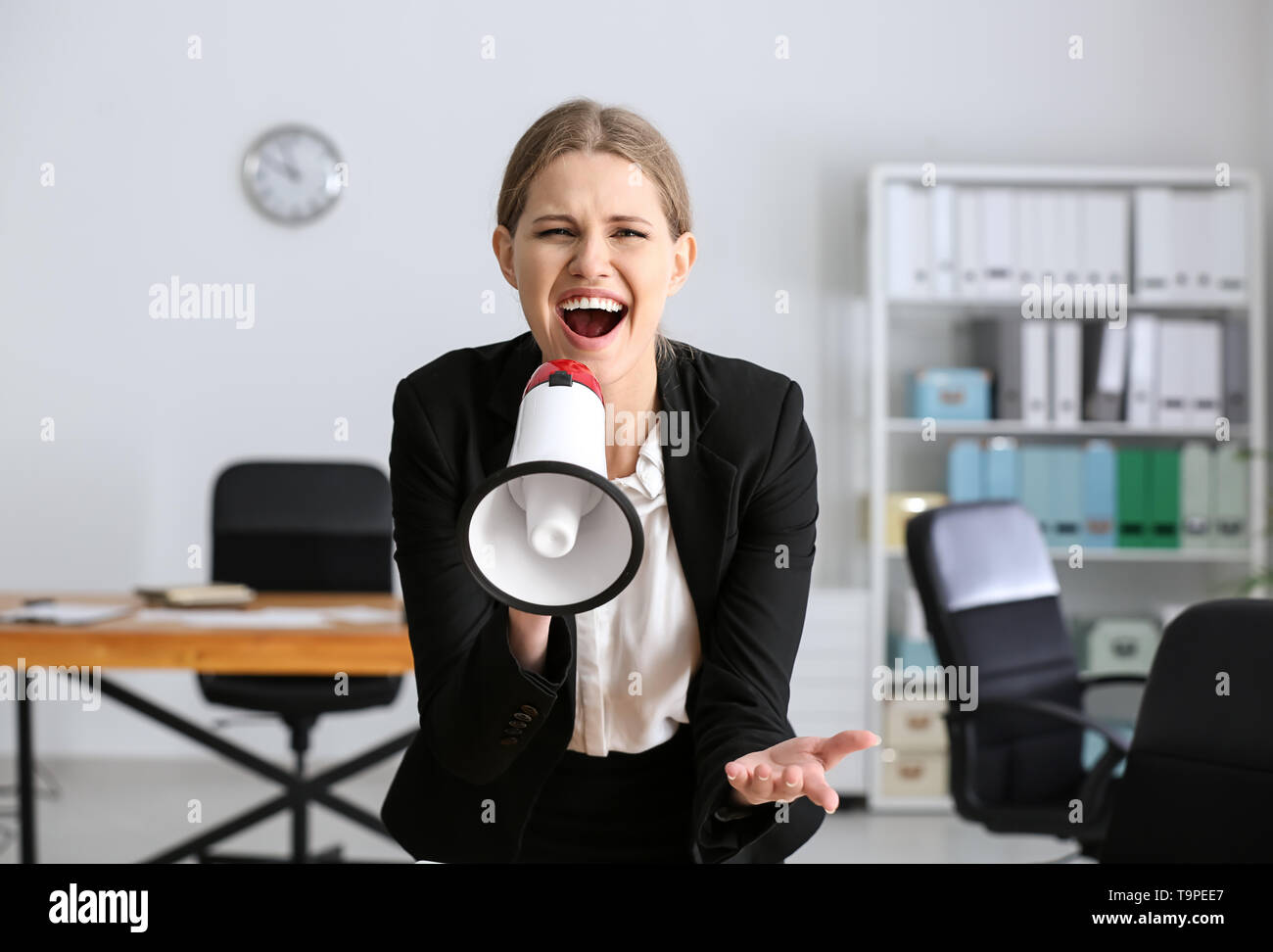 Young businesswoman using megaphone in office Stock Photo - Alamy