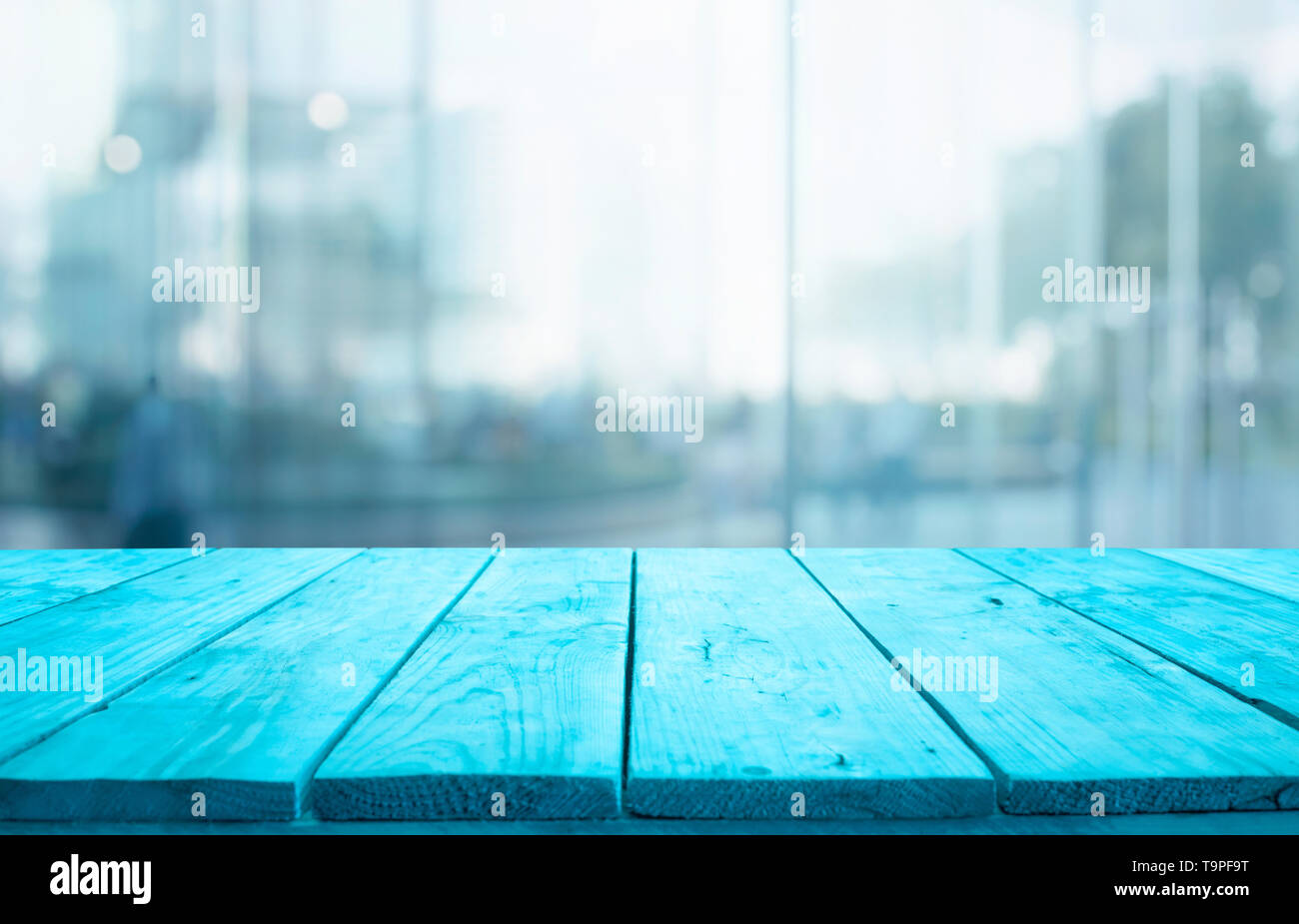 Blue wood table top on blur window glass,wall background with city view ...