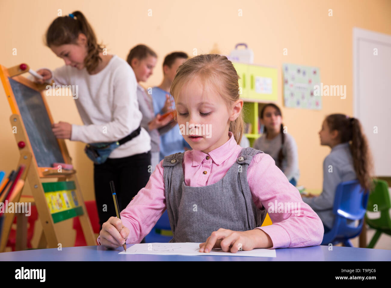 Little schoolgirl drawing in break between lessons in elementary school ...
