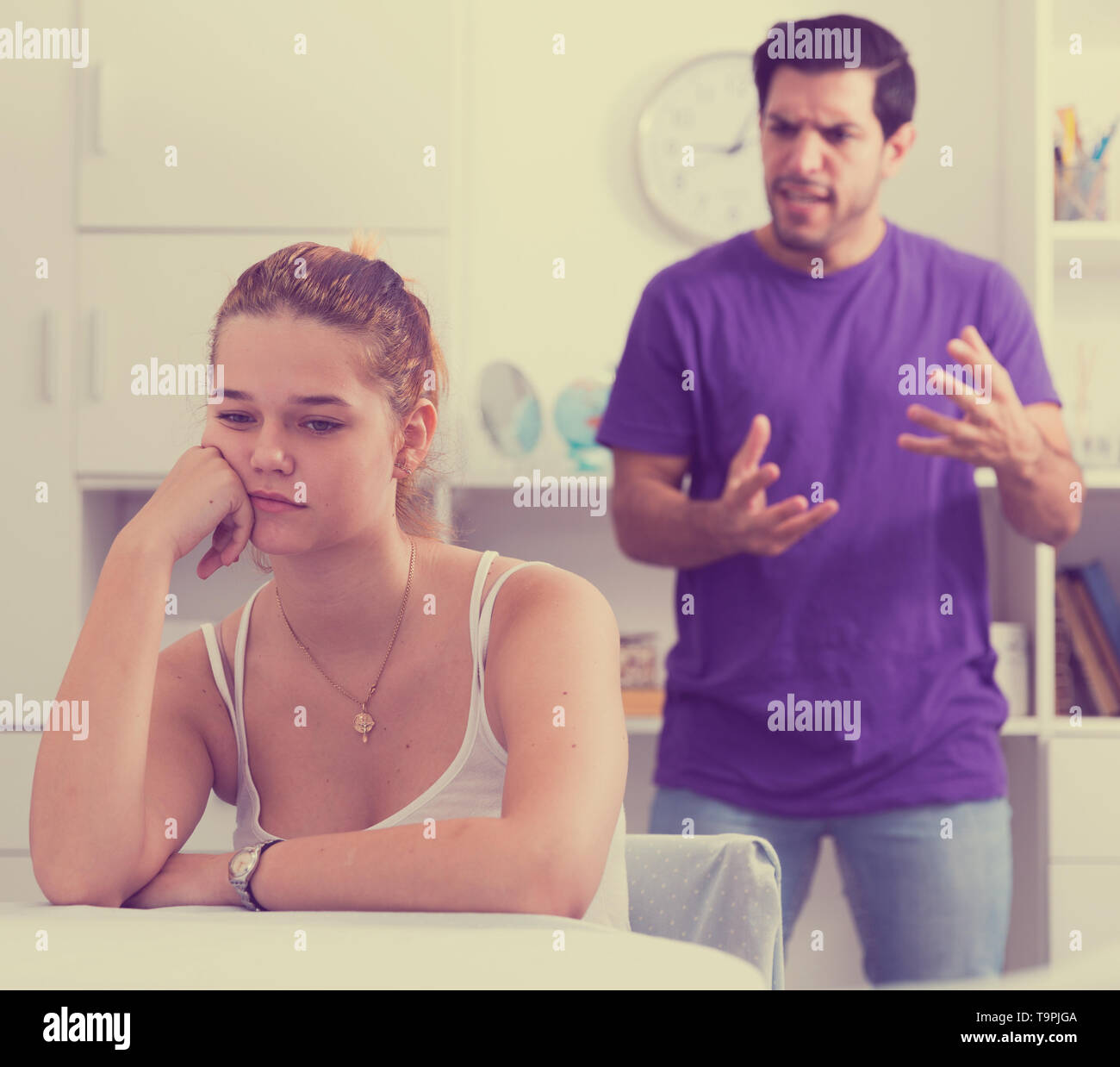 Upset young woman sitting at home table with disgruntled man behind ...