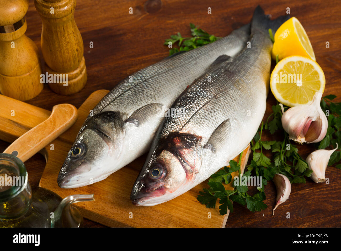 Two fresh raw sea bass fish with parsley, garlic and lemon Stock Photo ...