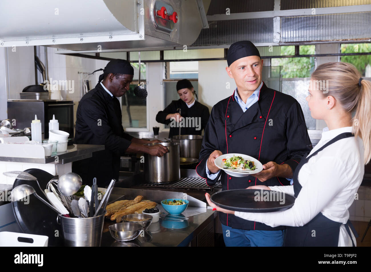 Head chef checking dishes in kitchen of restaurant before serving ...