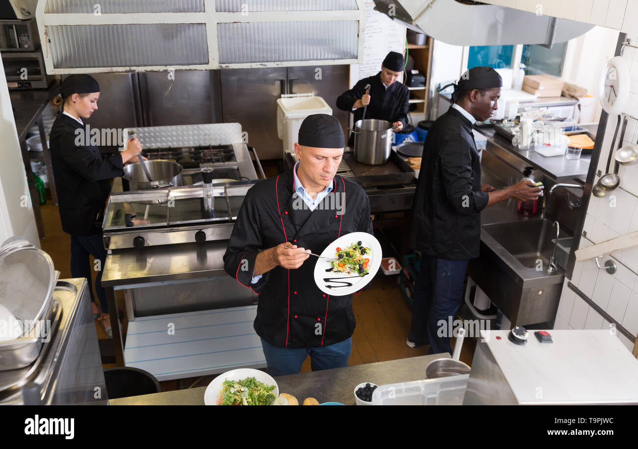 Head chef checking dishes in kitchen of restaurant before serving ...