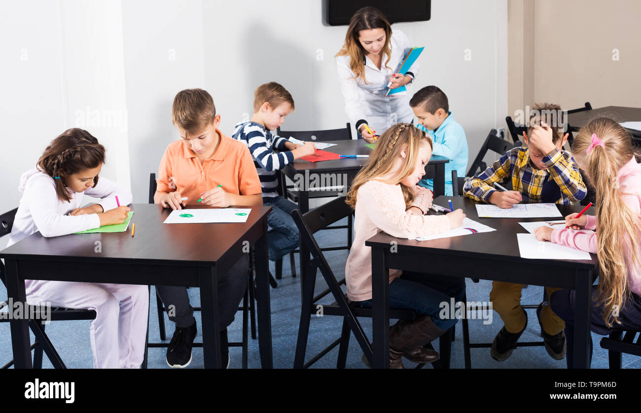 Positive young boys and girls with teacher drawing in classroom Stock ...