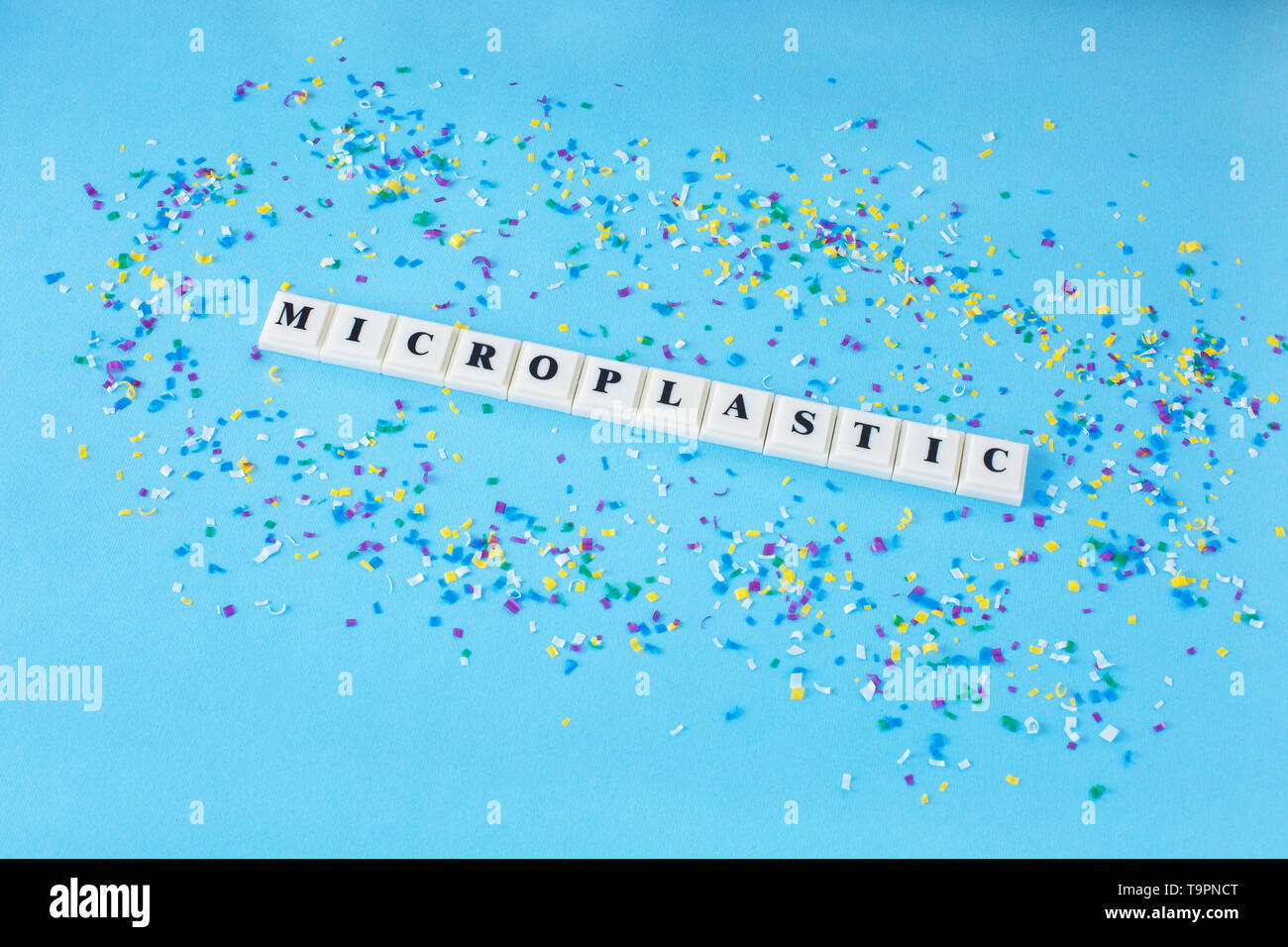 Word MICROPLASTIC around small plastic particles on a blue background ...