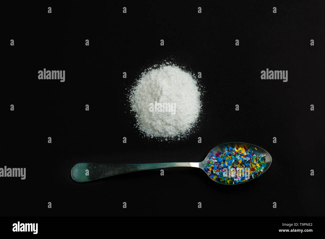 Microplastic in spoon which is taken from sea salt on a black ...