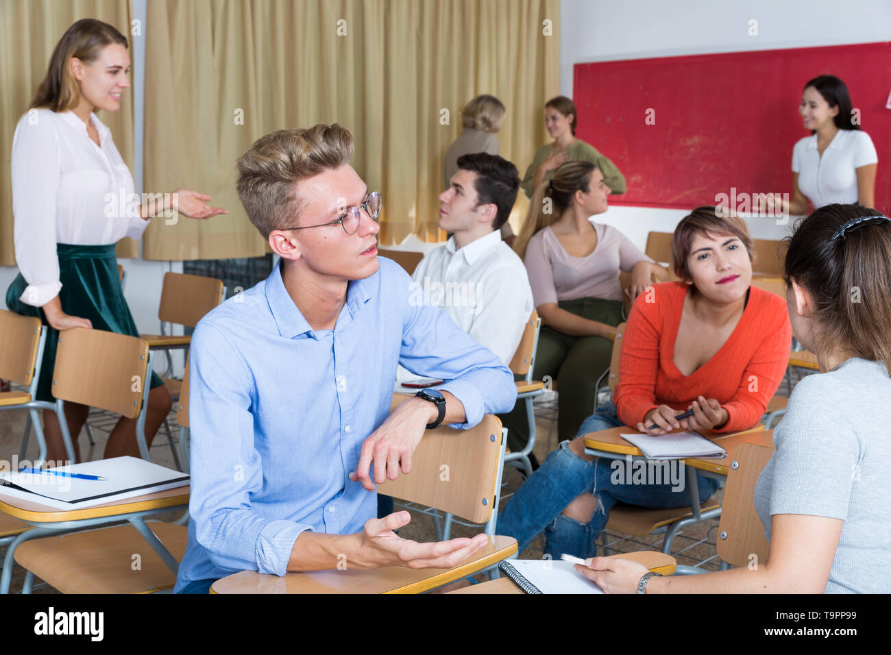 Happy group of adult students lively chatting while enjoying free time ...
