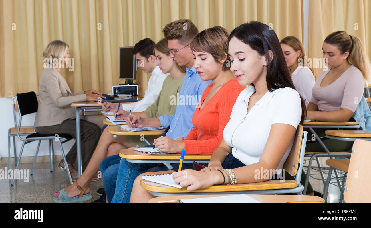 Side view of student group working with female teacher on lecture in ...