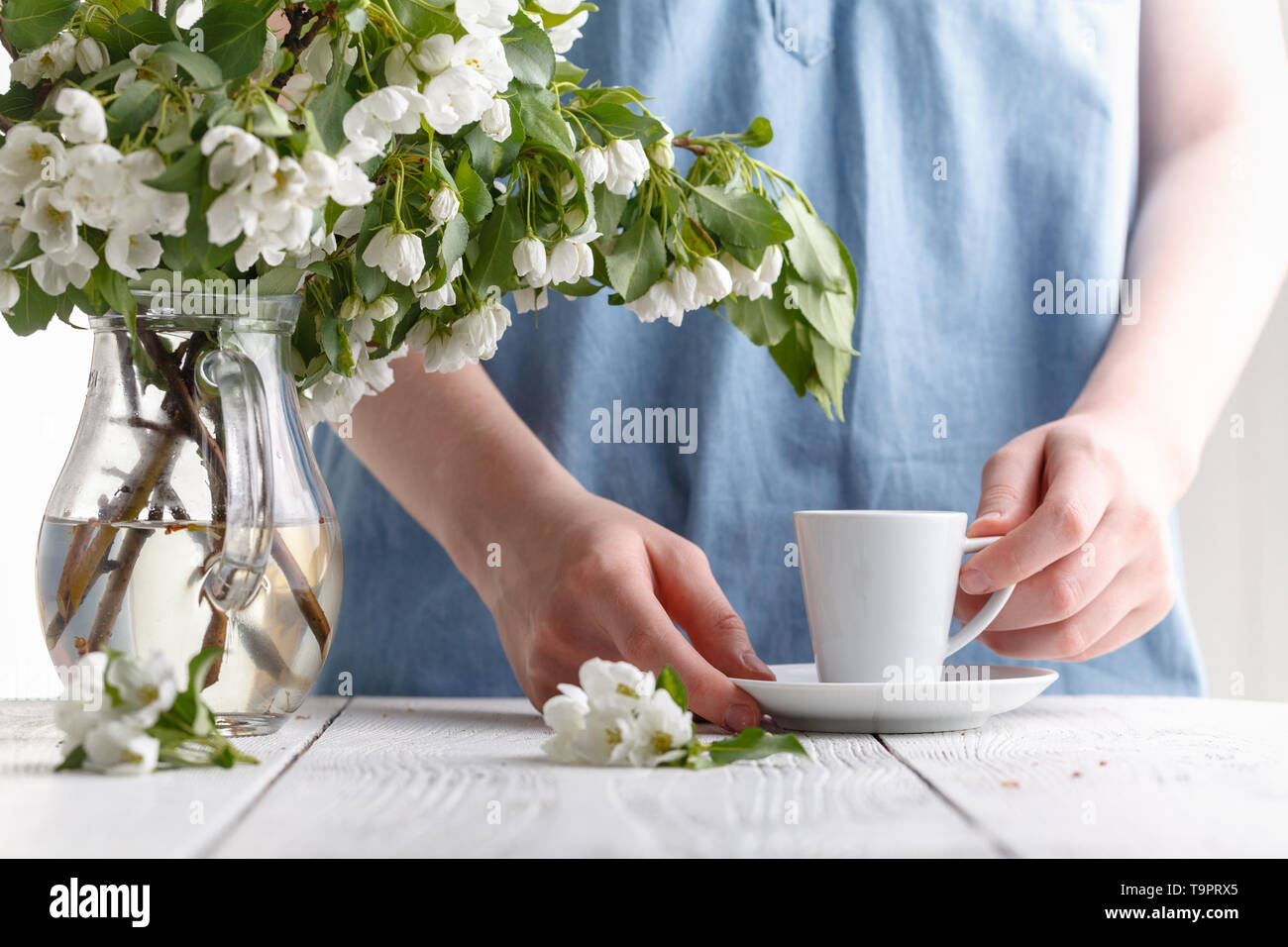 spring morning, the girl drinks coffee with a bouquet of spring flowers ...
