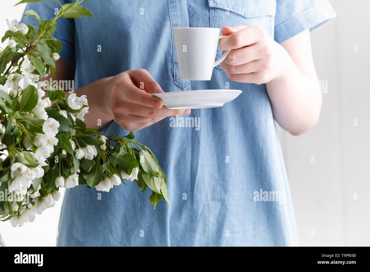 spring morning, the girl drinks coffee with a bouquet of spring flowers ...
