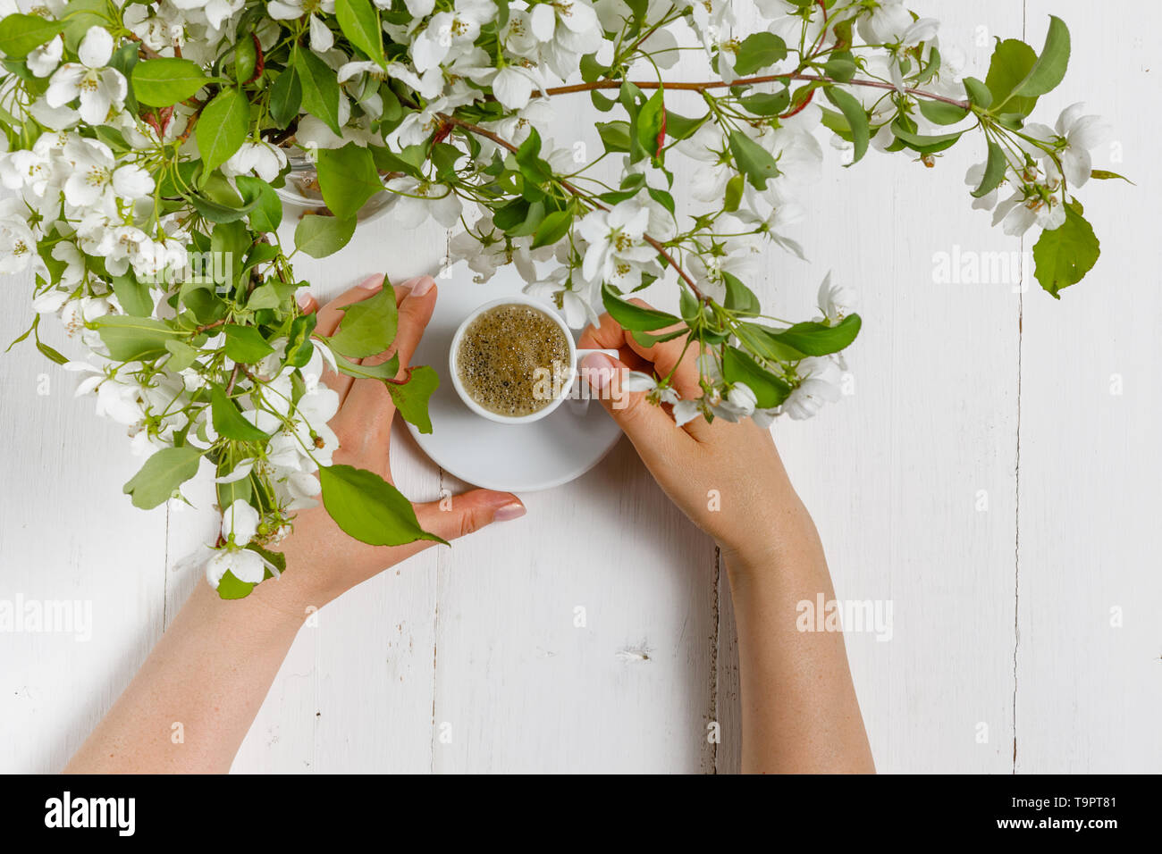 spring morning, the girl drinks coffee with a bouquet of spring flowers ...