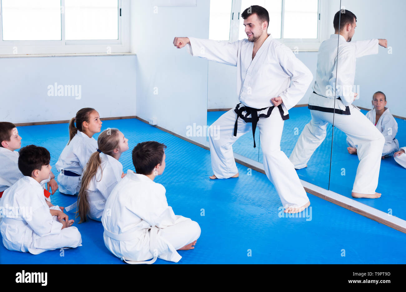 Young man training new karate moves with teenagers during class Stock ...
