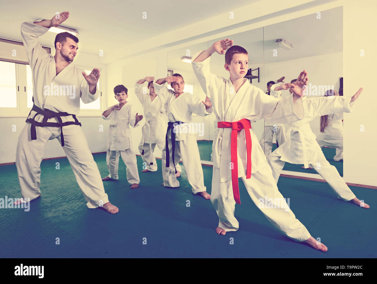 Group of children training with coach a new moves during karate class ...