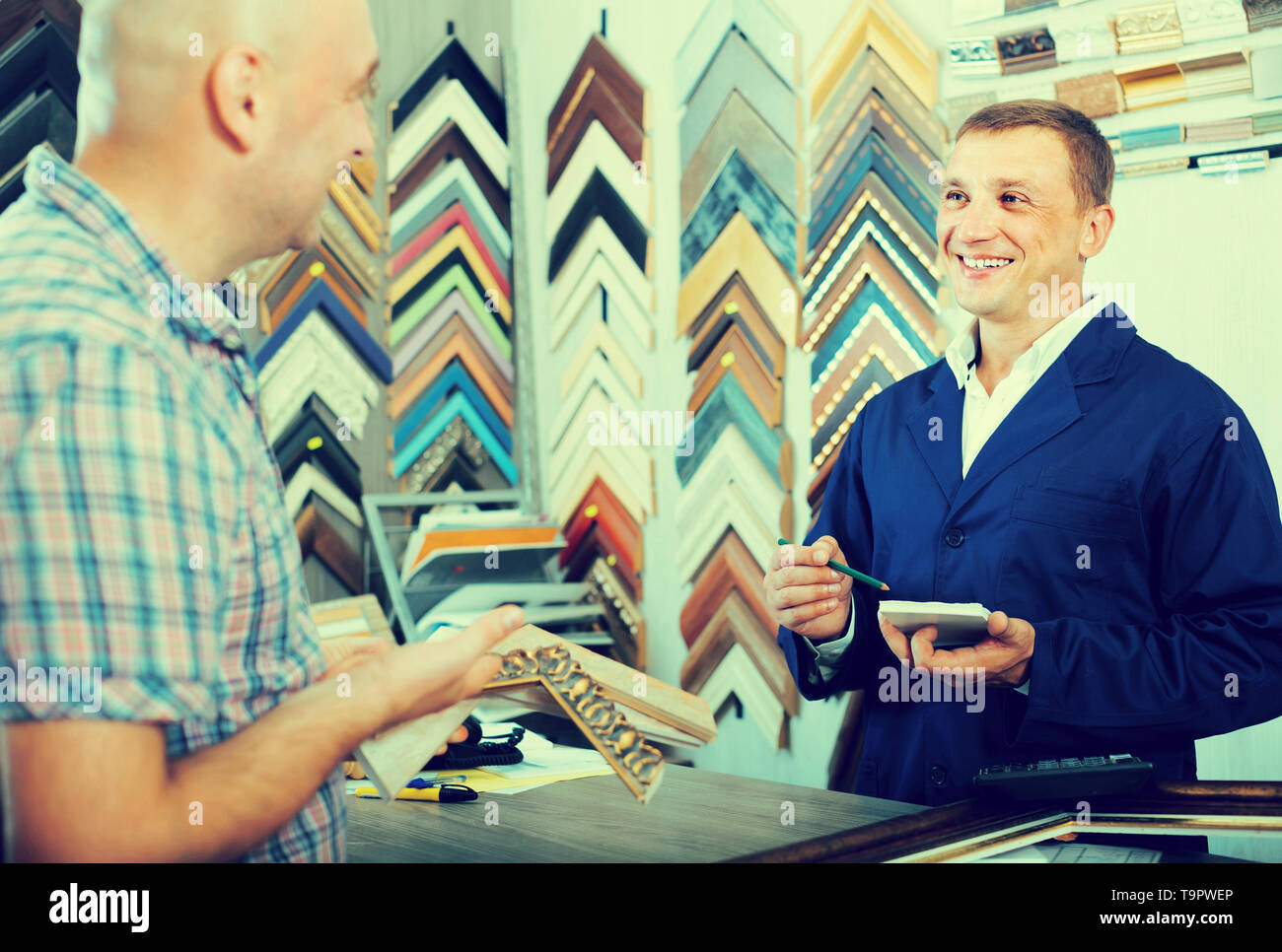 portrait of glad spanish man seller taking order on picture frame from ...