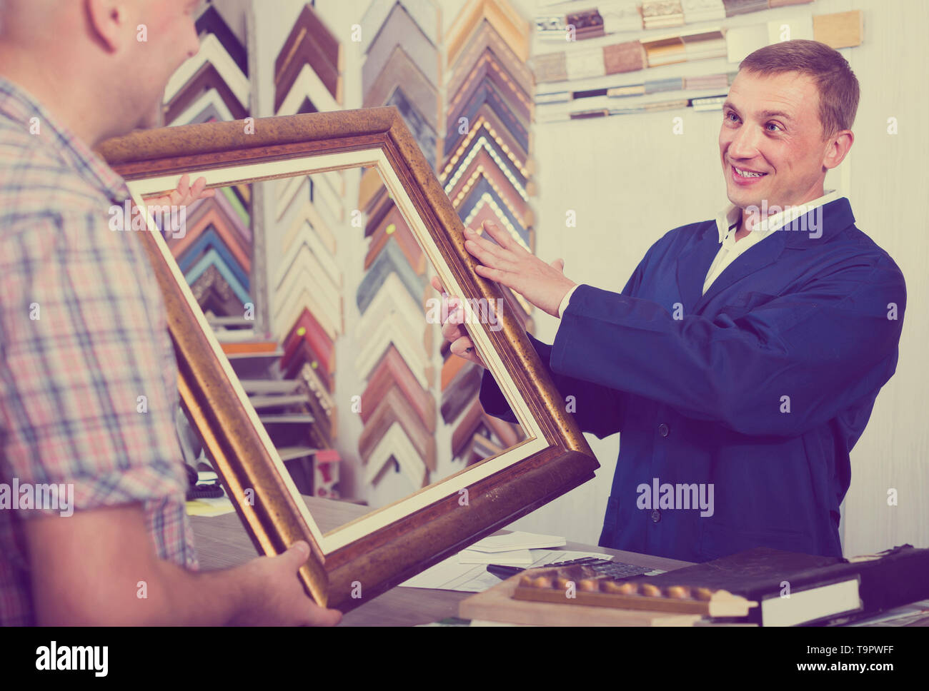 portrait of glad american man seller taking order on picture frame from ...