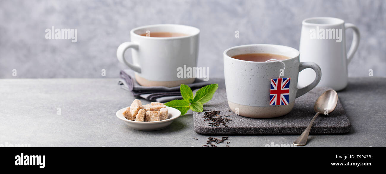 Tea in mugs with British flag tea bag label. Grey background. Copy ...