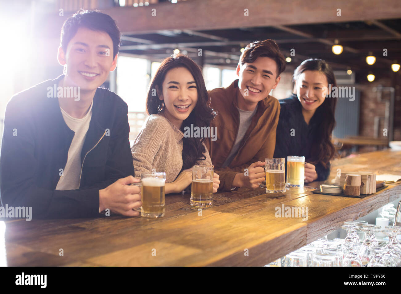 Happy friends drinking beer in bar Stock Photo - Alamy