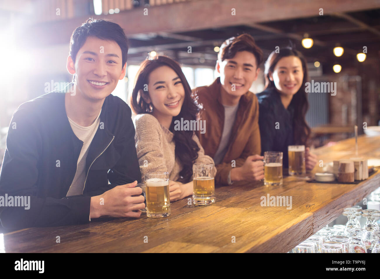 Happy friends drinking beer in bar Stock Photo - Alamy
