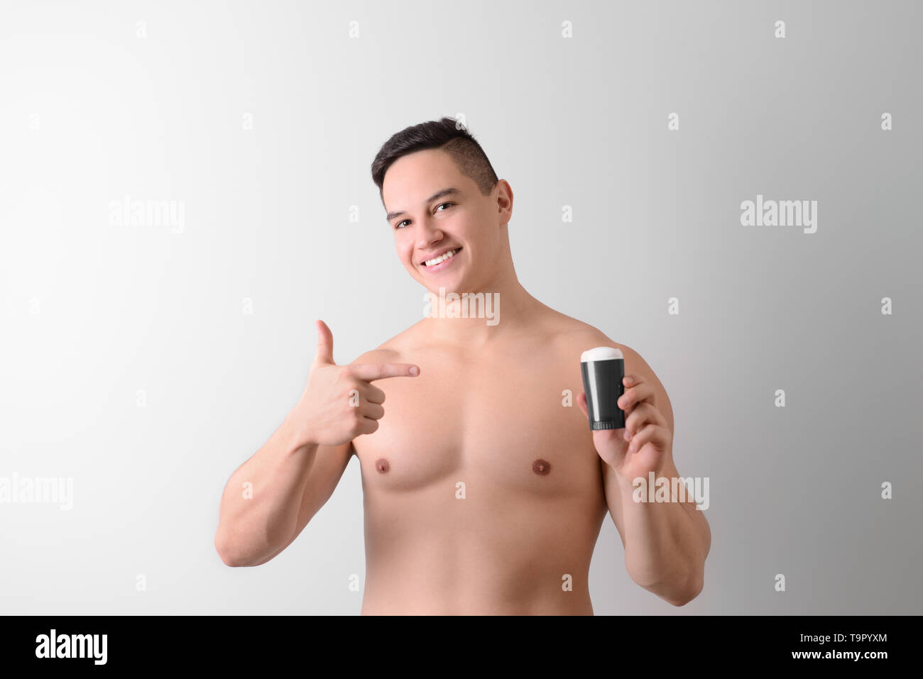 Young man with deodorant on light background Stock Photo - Alamy