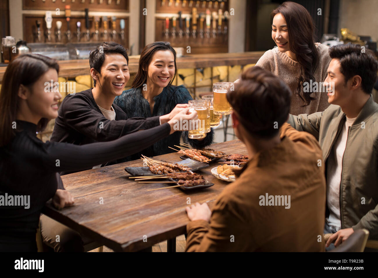 Happy friends toasting and talking in bar Stock Photo - Alamy