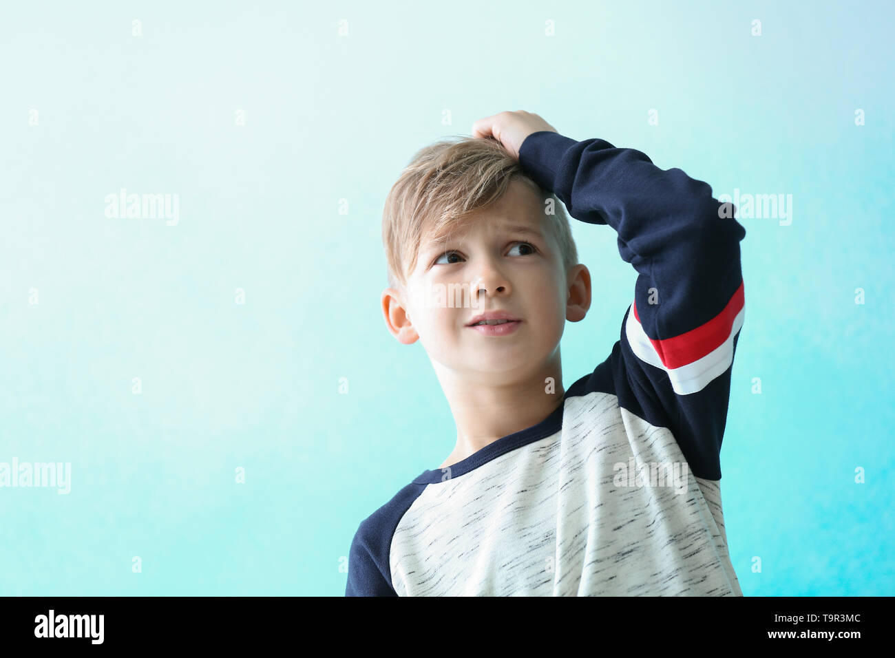 Cute confused boy on color background Stock Photo - Alamy
