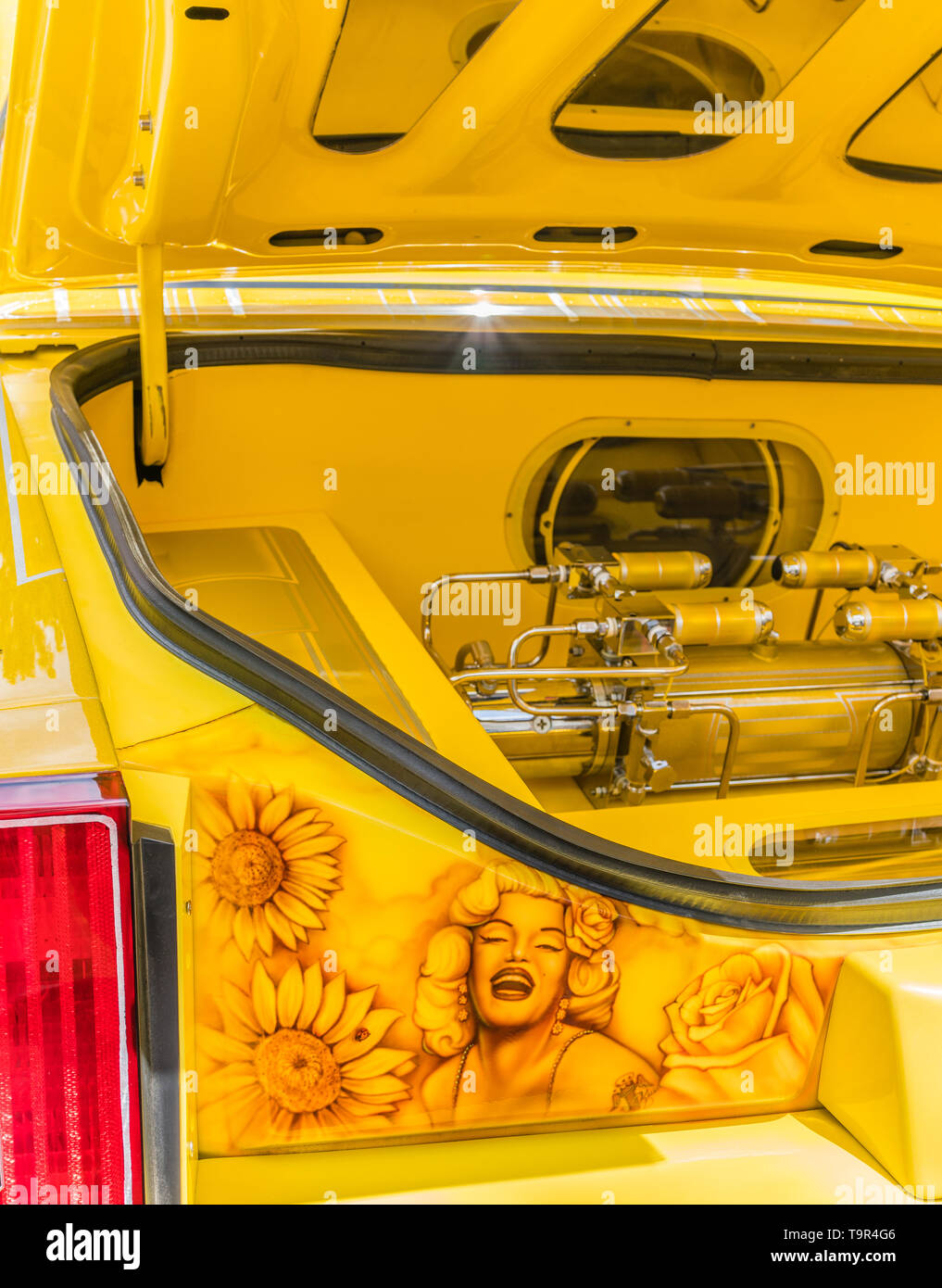 A detail of the trunk of a bright yellow Chevrolet lowrider car that ...