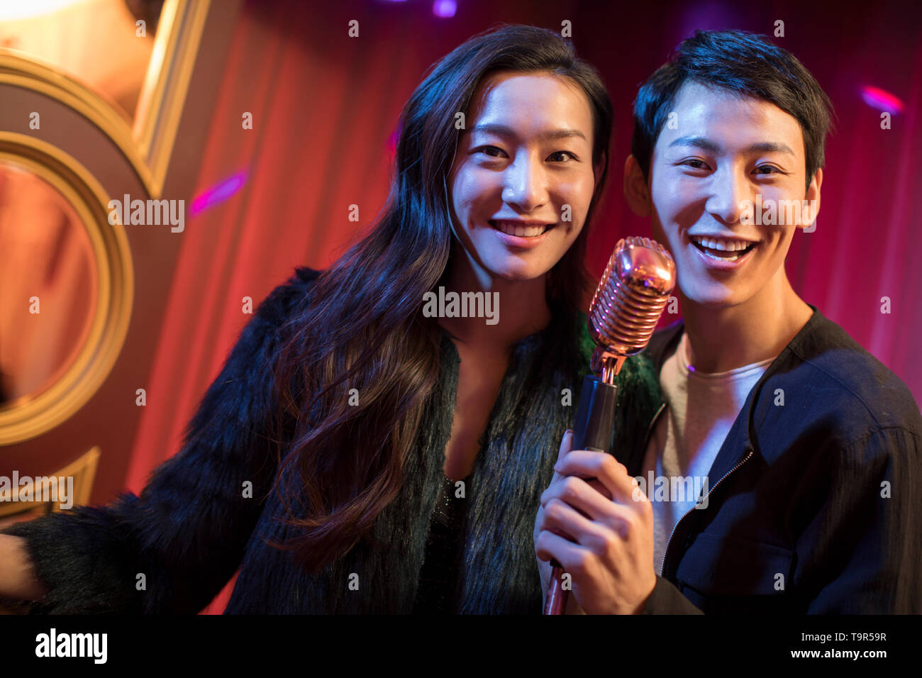 Happy young couple singing karaoke in nightclub Stock Photo - Alamy