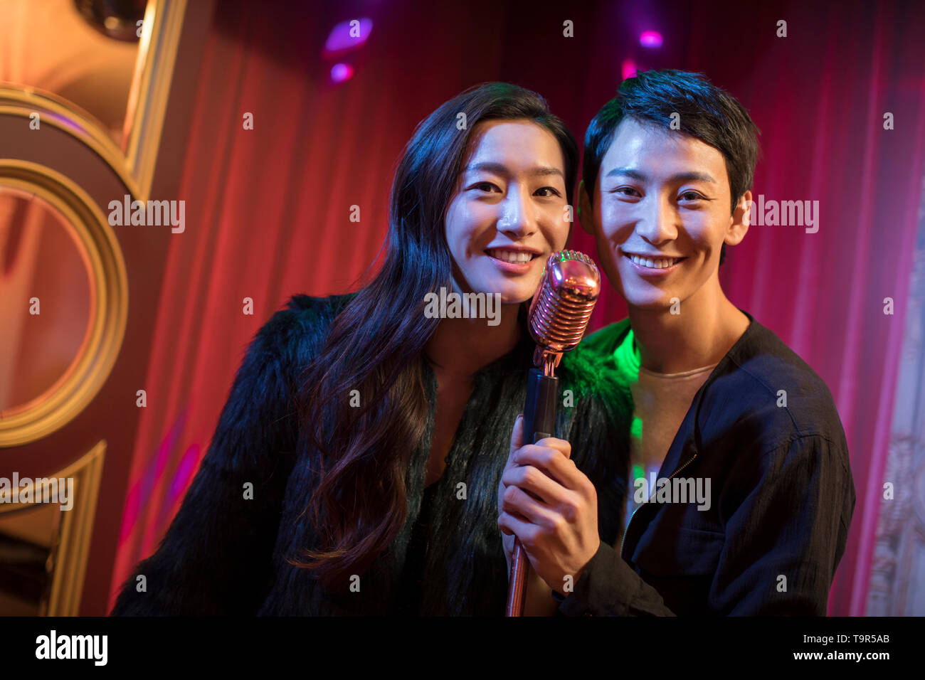 Happy young couple singing karaoke in nightclub Stock Photo - Alamy