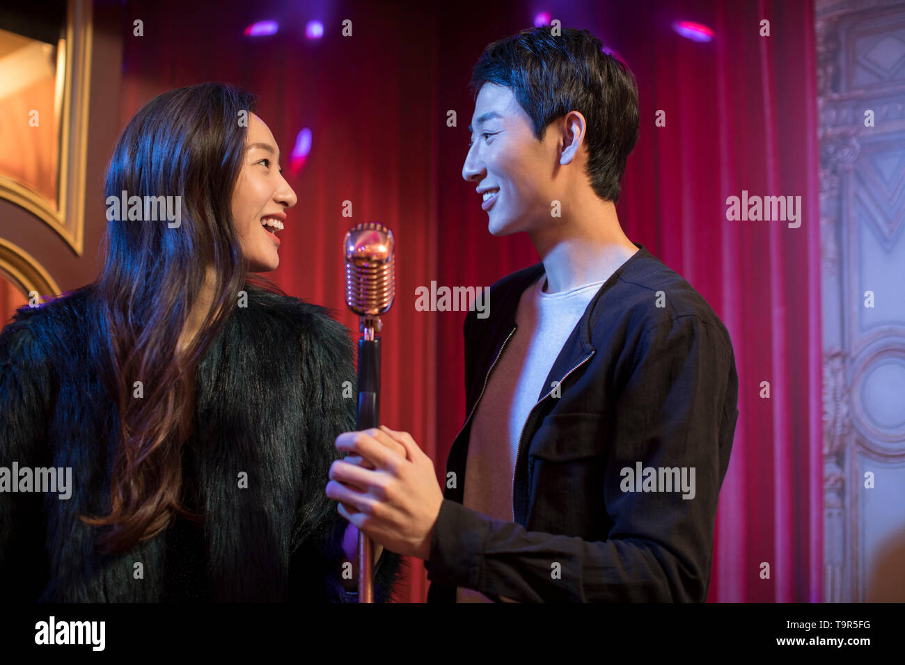 Happy young couple singing karaoke in nightclub Stock Photo - Alamy