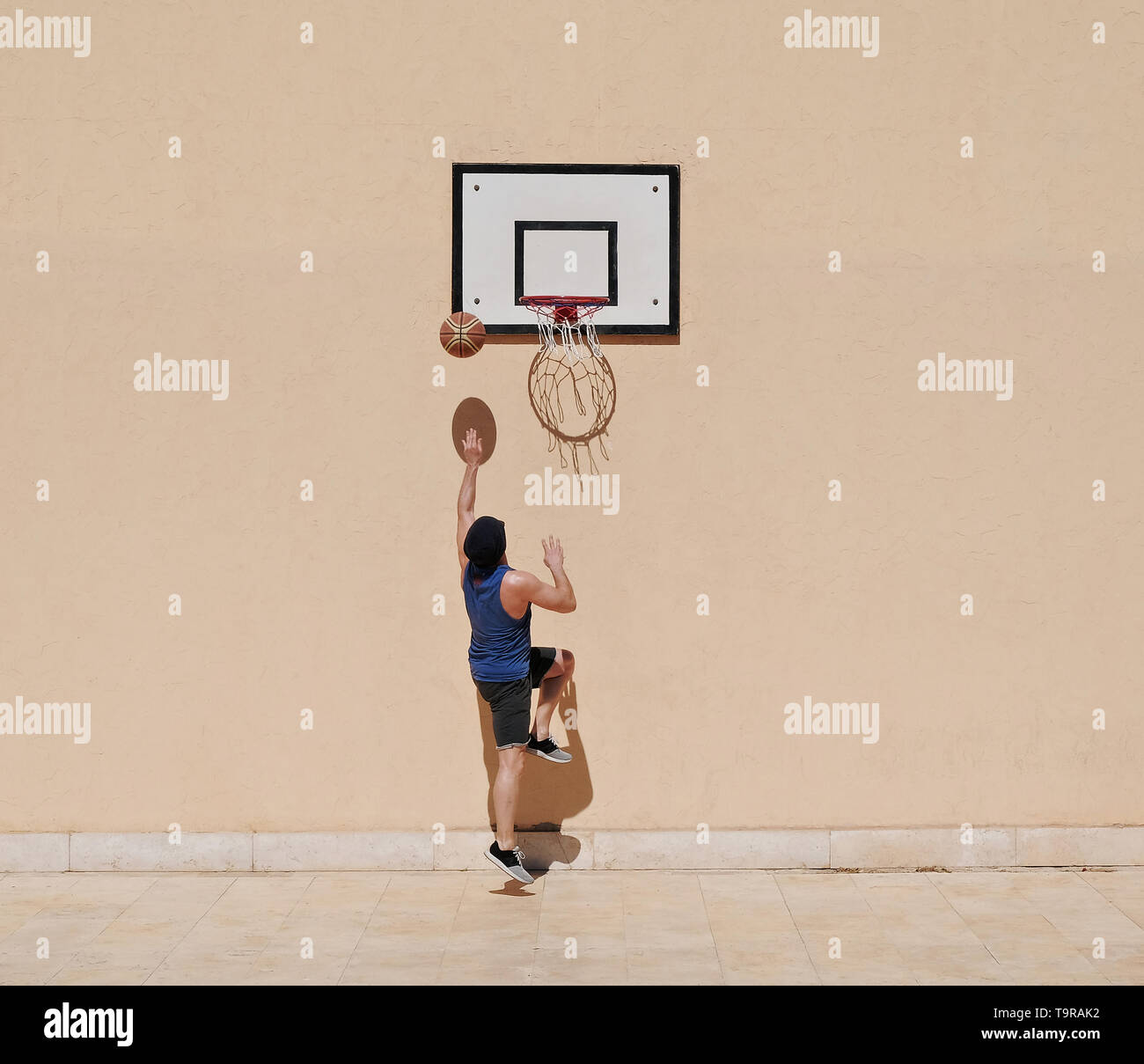 One man is playing basketball on his own. The ball and the hoop are ...