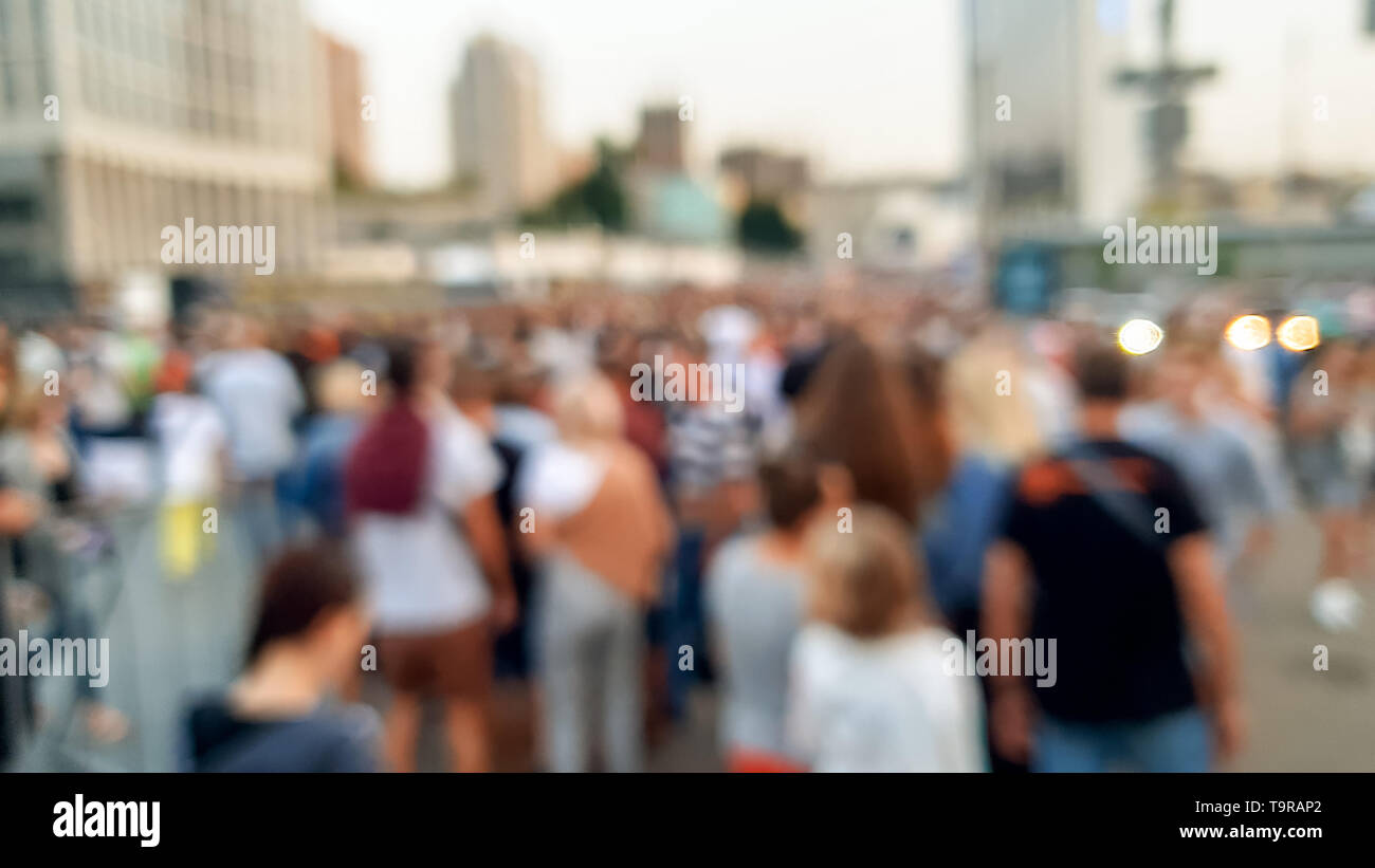 Blurred image of big crowd of people standing on the city street ...