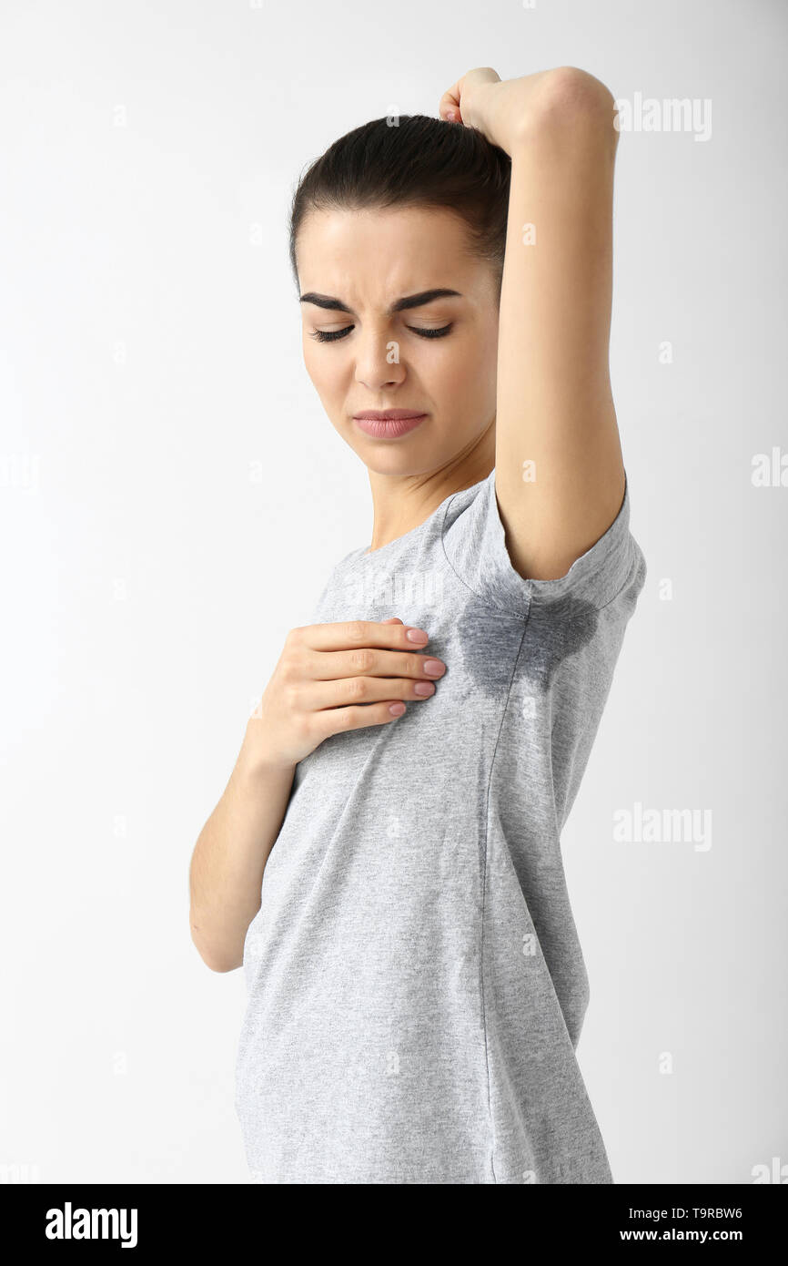 Young woman with wet spot on clothes under armpit against white ...