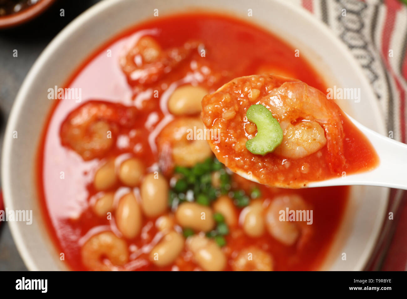 Spoon with tasty Chinese soup over plate, closeup Stock Photo - Alamy