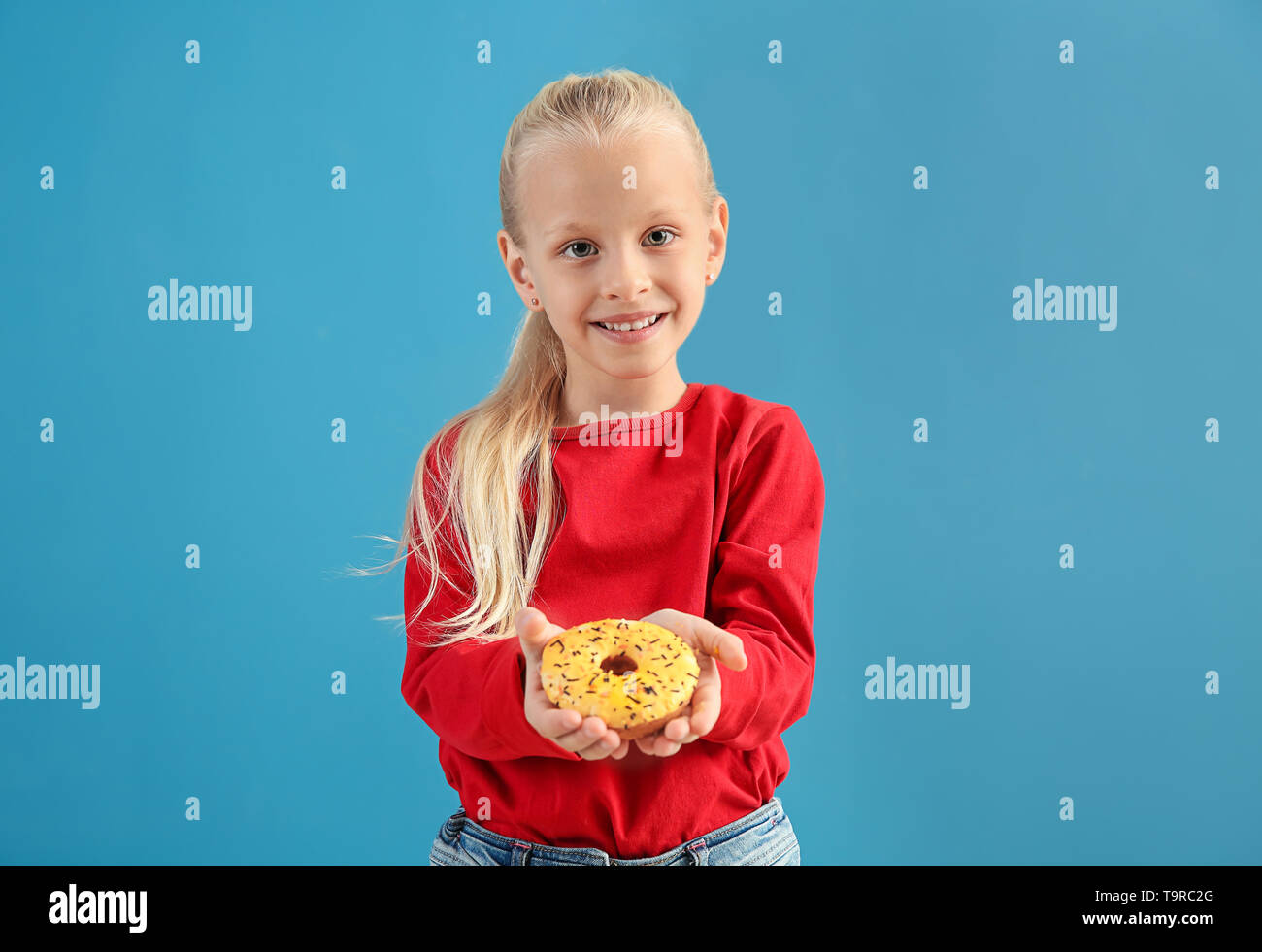 Cute little girl with donut on color background Stock Photo - Alamy