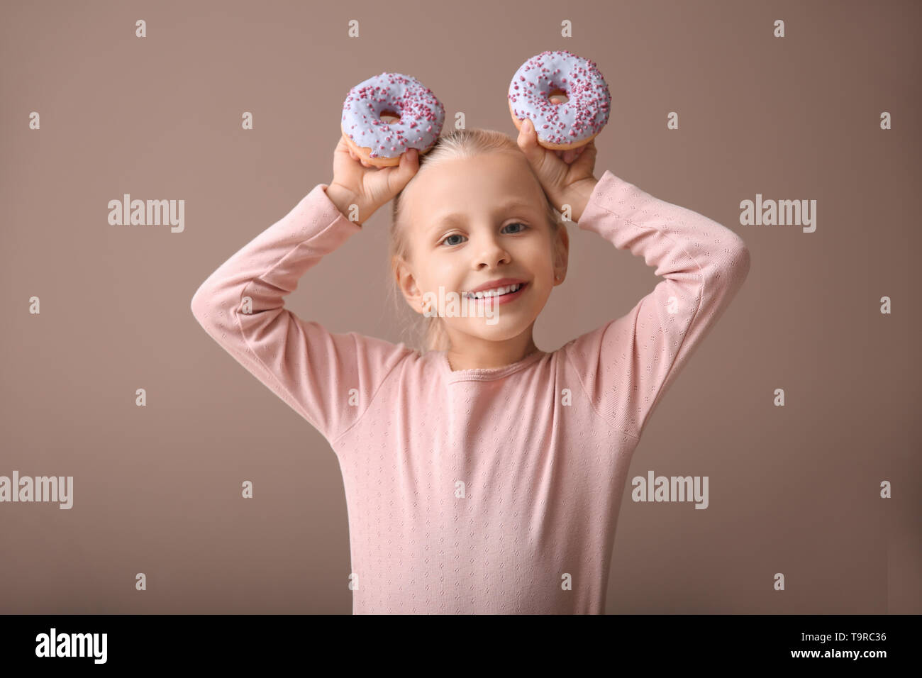Cute little girl with donuts on color background Stock Photo - Alamy