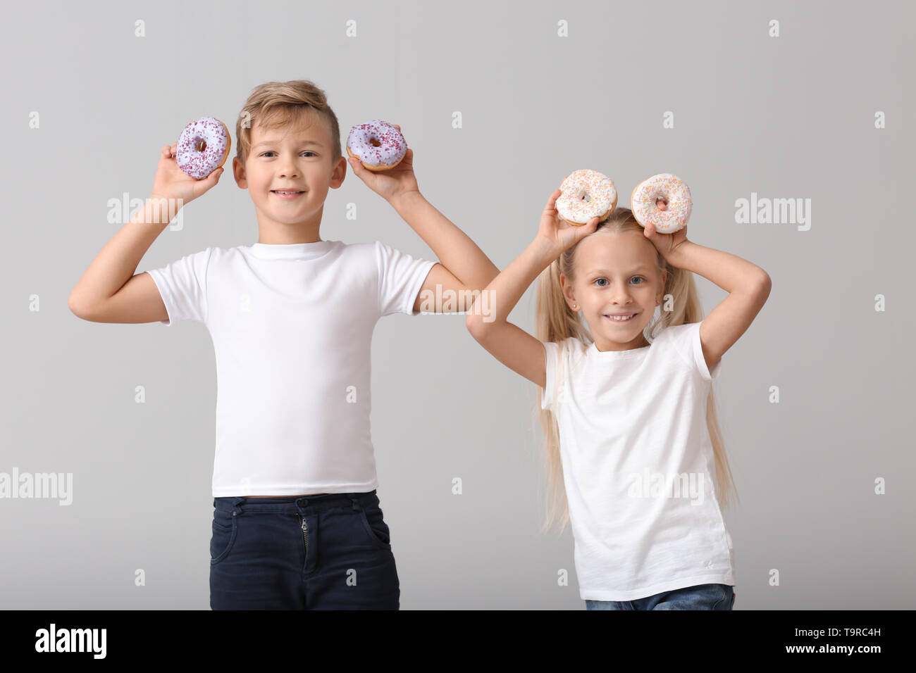 Cute little children with donuts on light background Stock Photo - Alamy