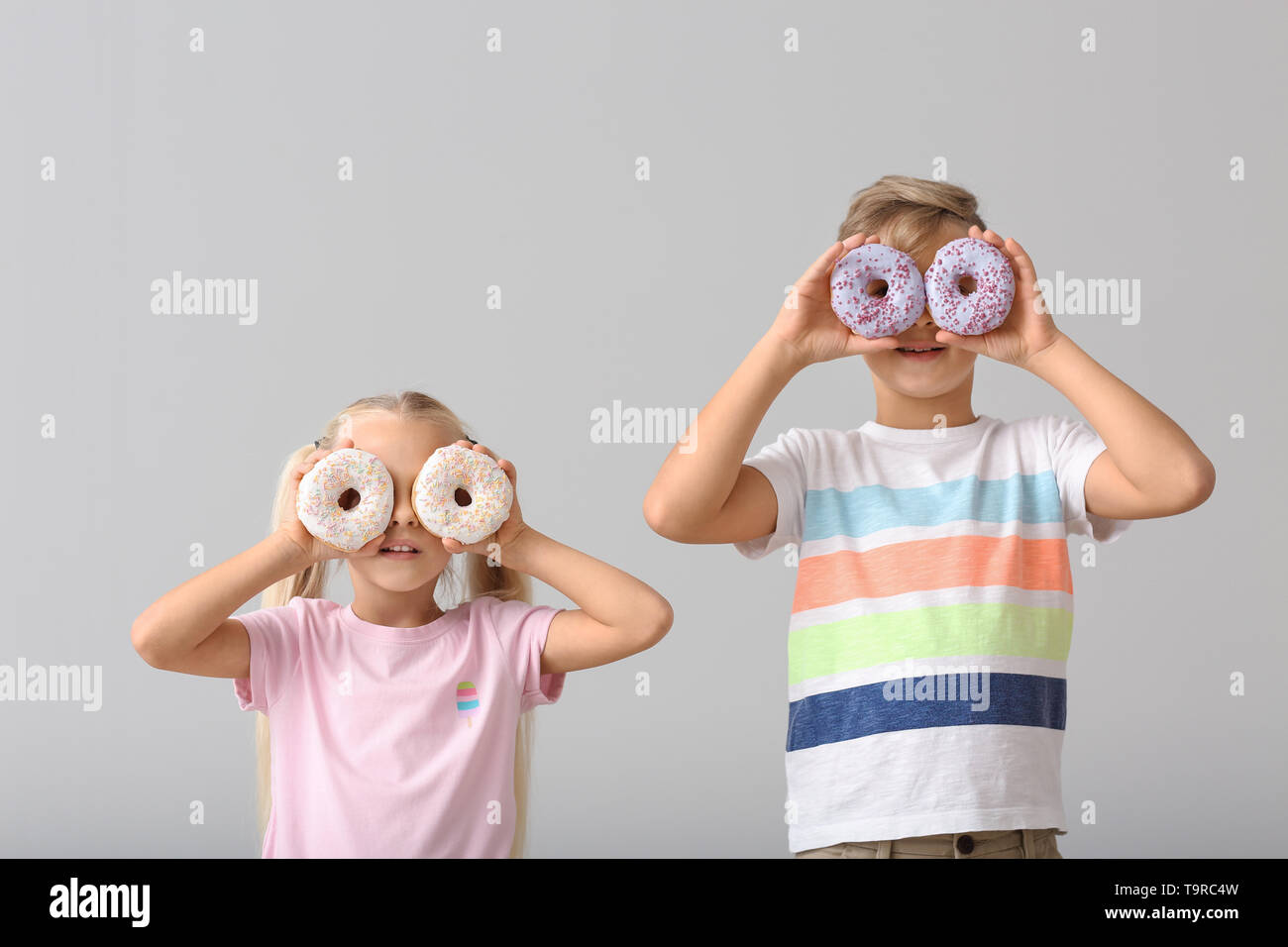 Cute little children with donuts on light background Stock Photo - Alamy