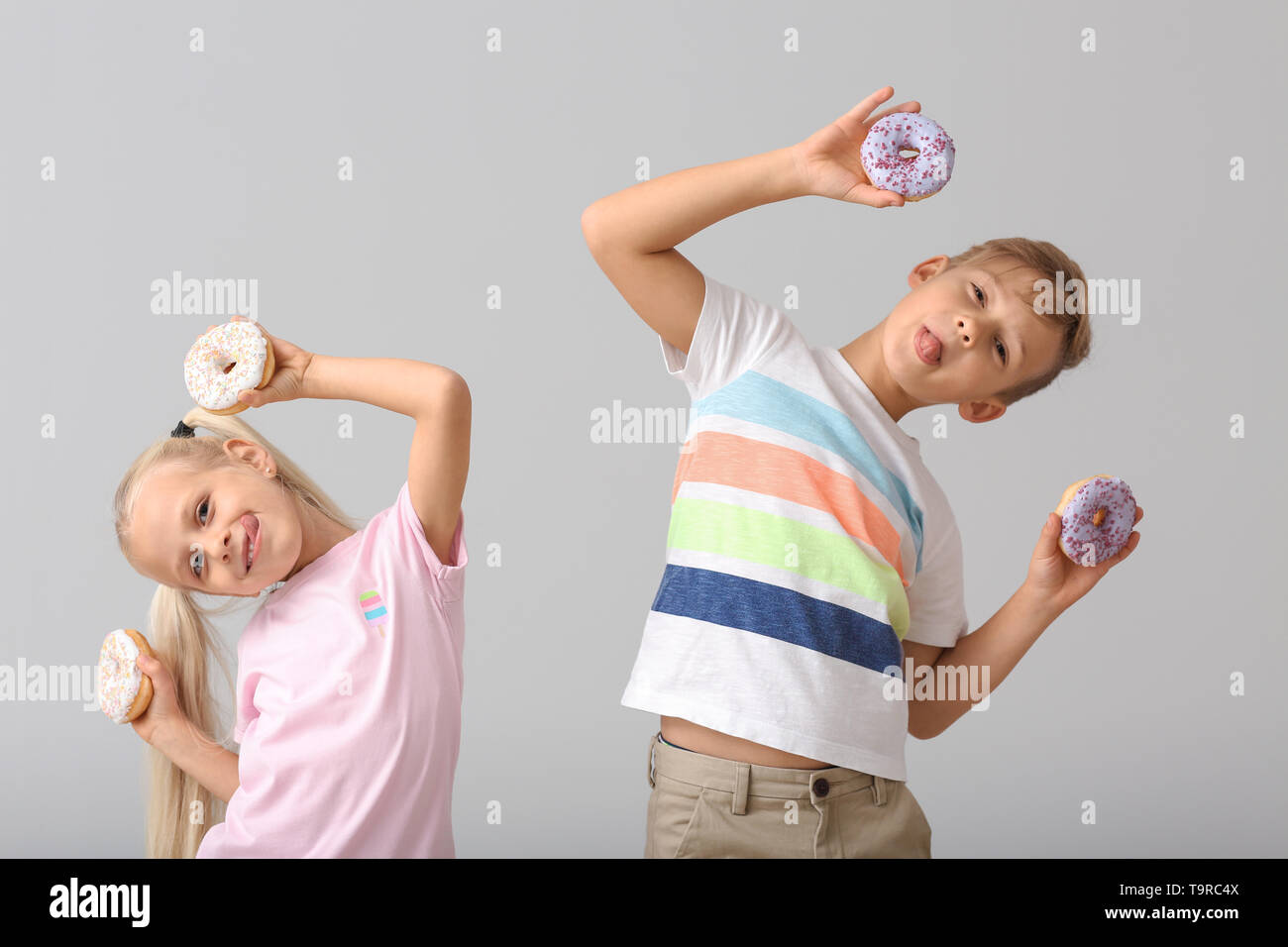 Cute little children with donuts on light background Stock Photo - Alamy