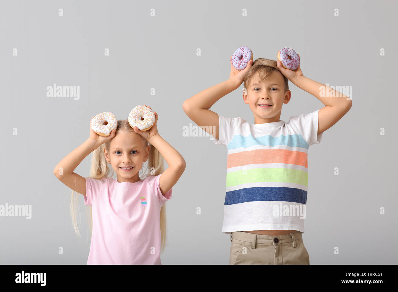 Cute little children with donuts on light background Stock Photo - Alamy